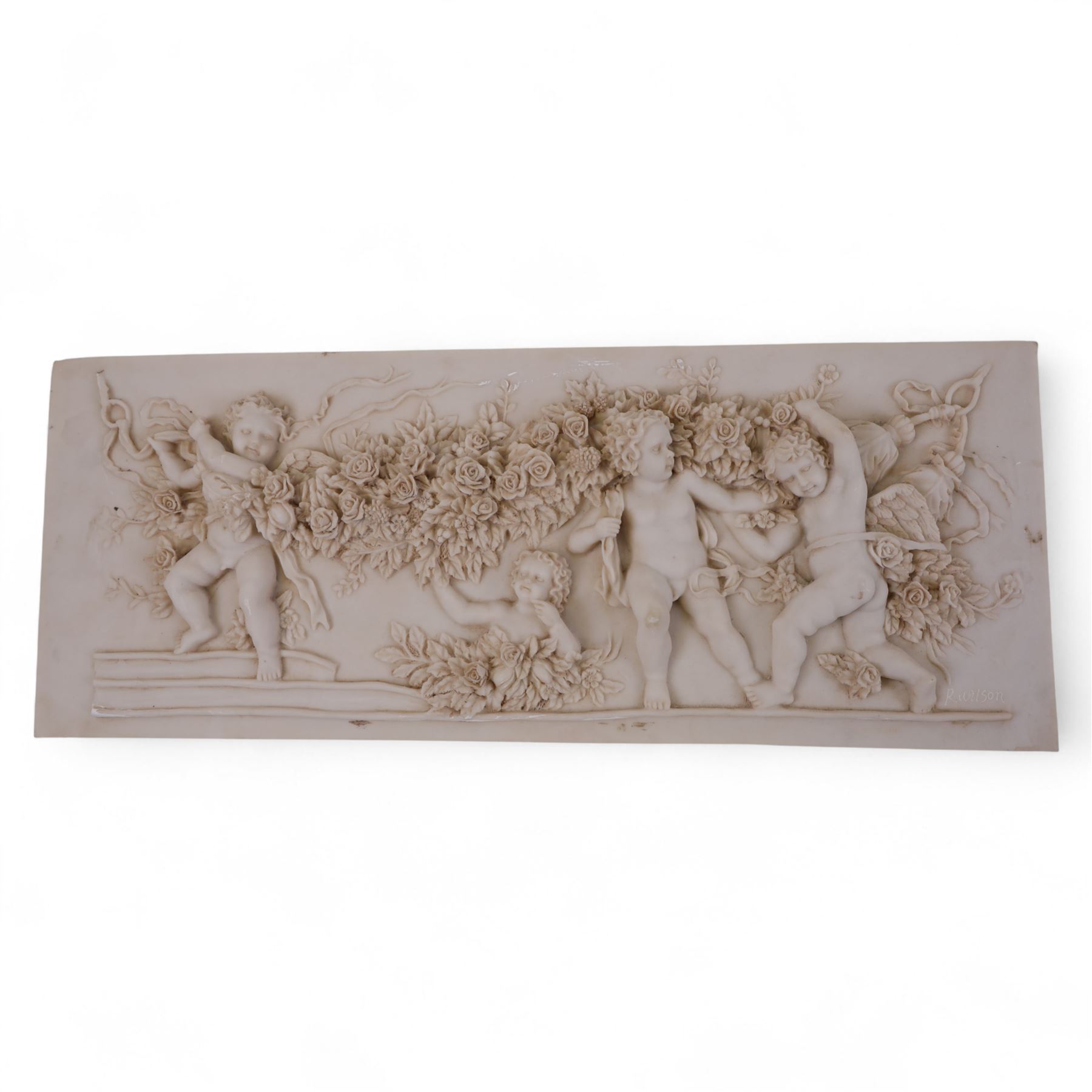 Composite plaque decorated in relief with putti amongst flowering roses ...
