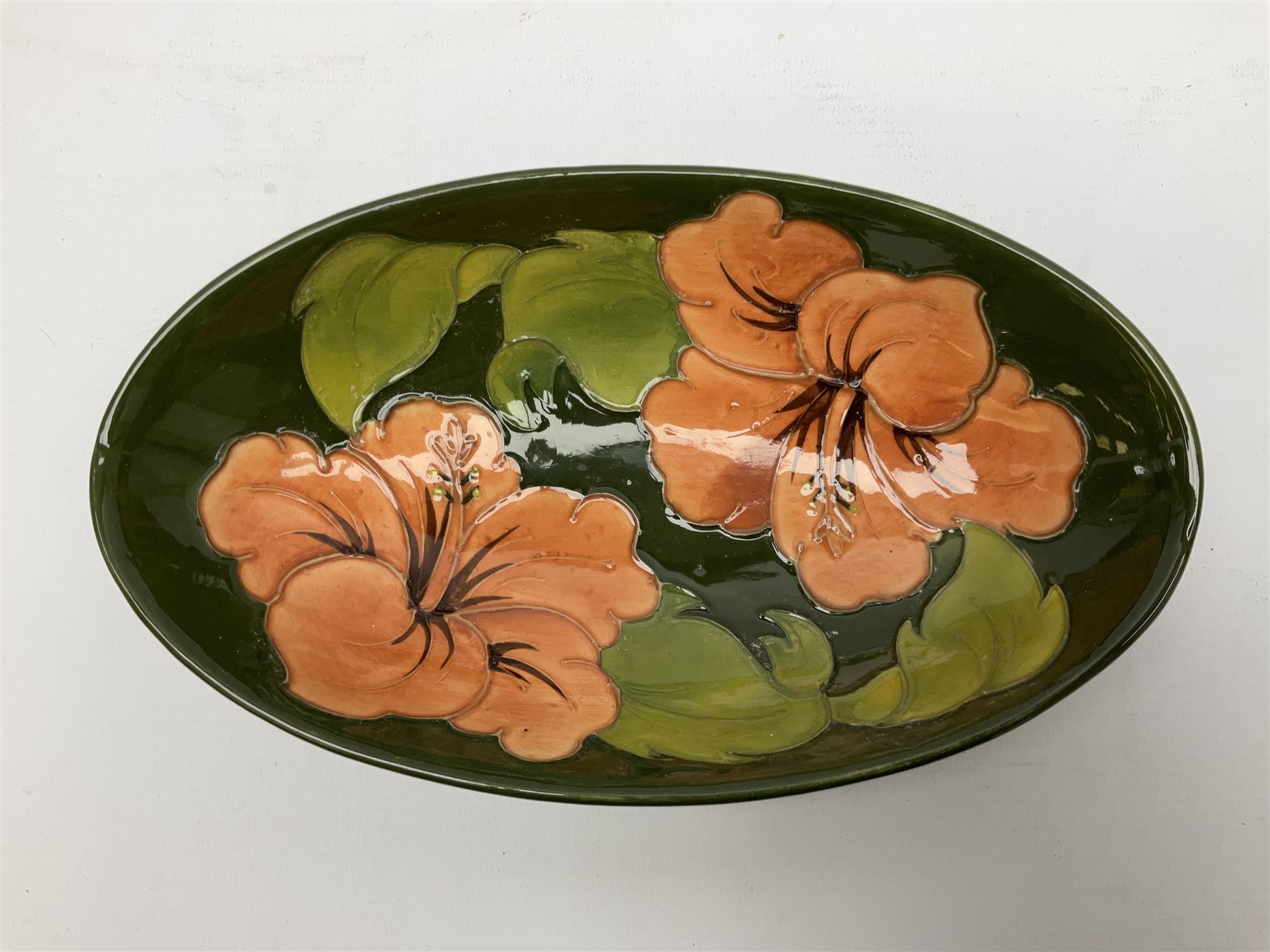 Moorcroft oval bowl, decorated in the Hibiscus pattern upon a green ...