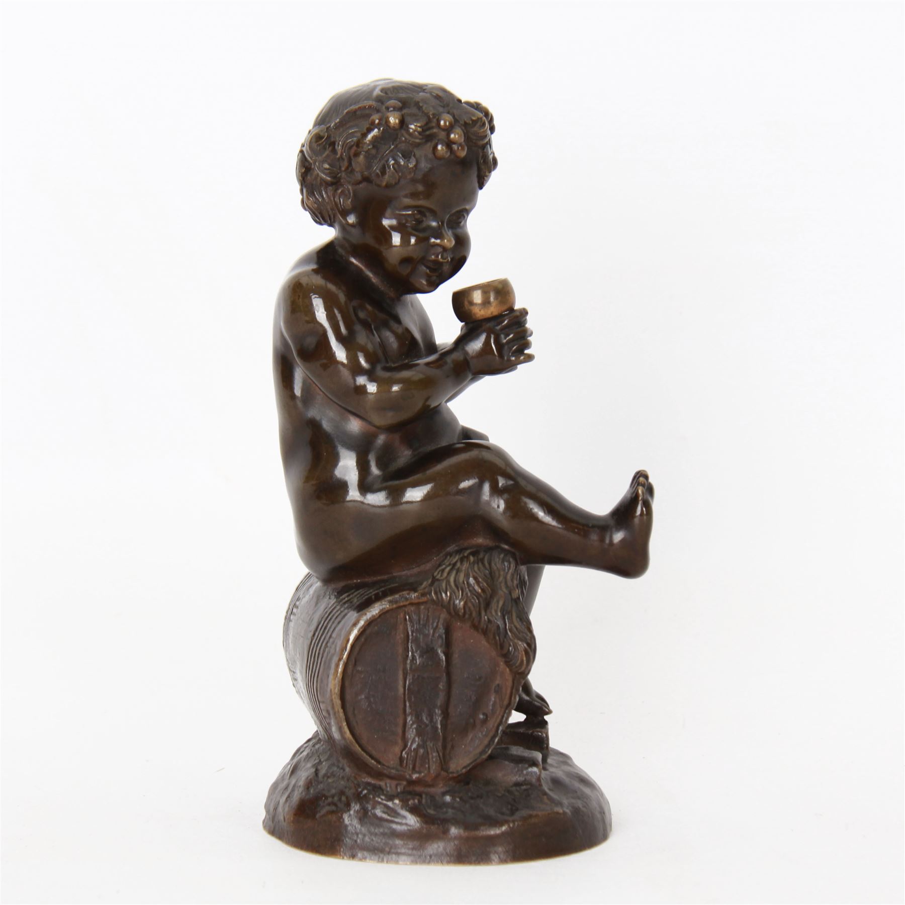 Bronzed metal model of a putti seated upon a barrel with goblet in ...