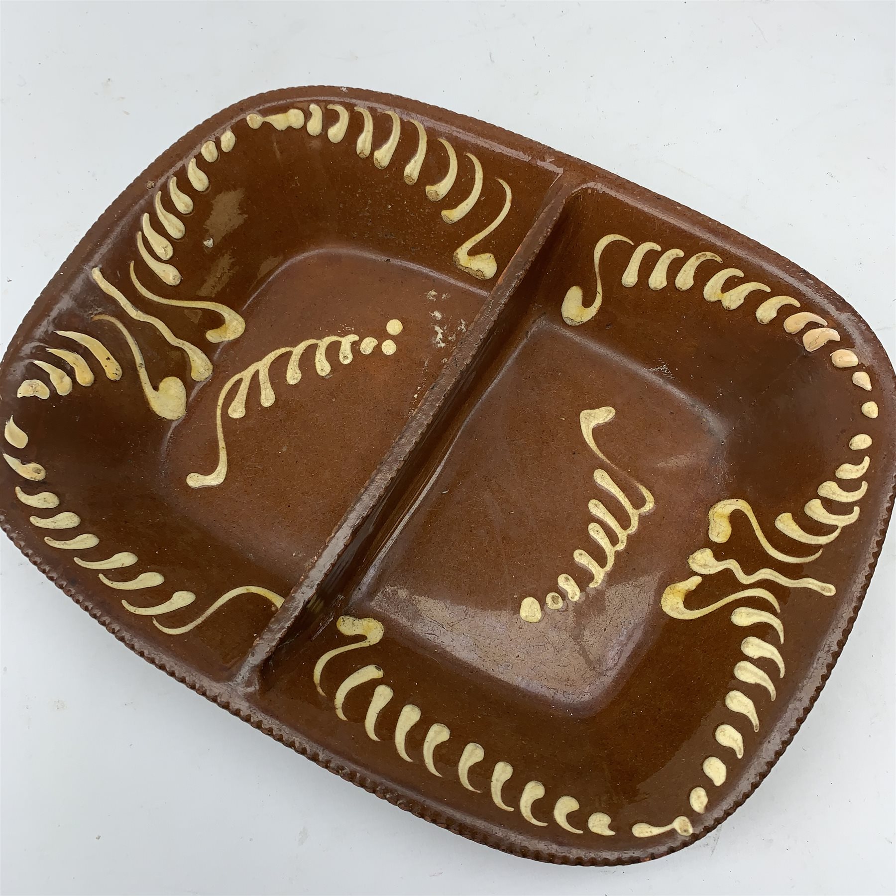 A Victorian terracotta two-division dish of rounded oblong form with ...